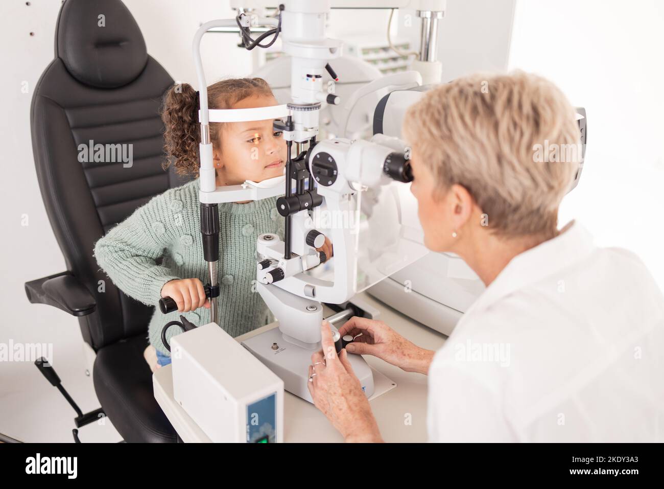 Girl child in eye exam for vision, woman optician checking kids eyes in ...