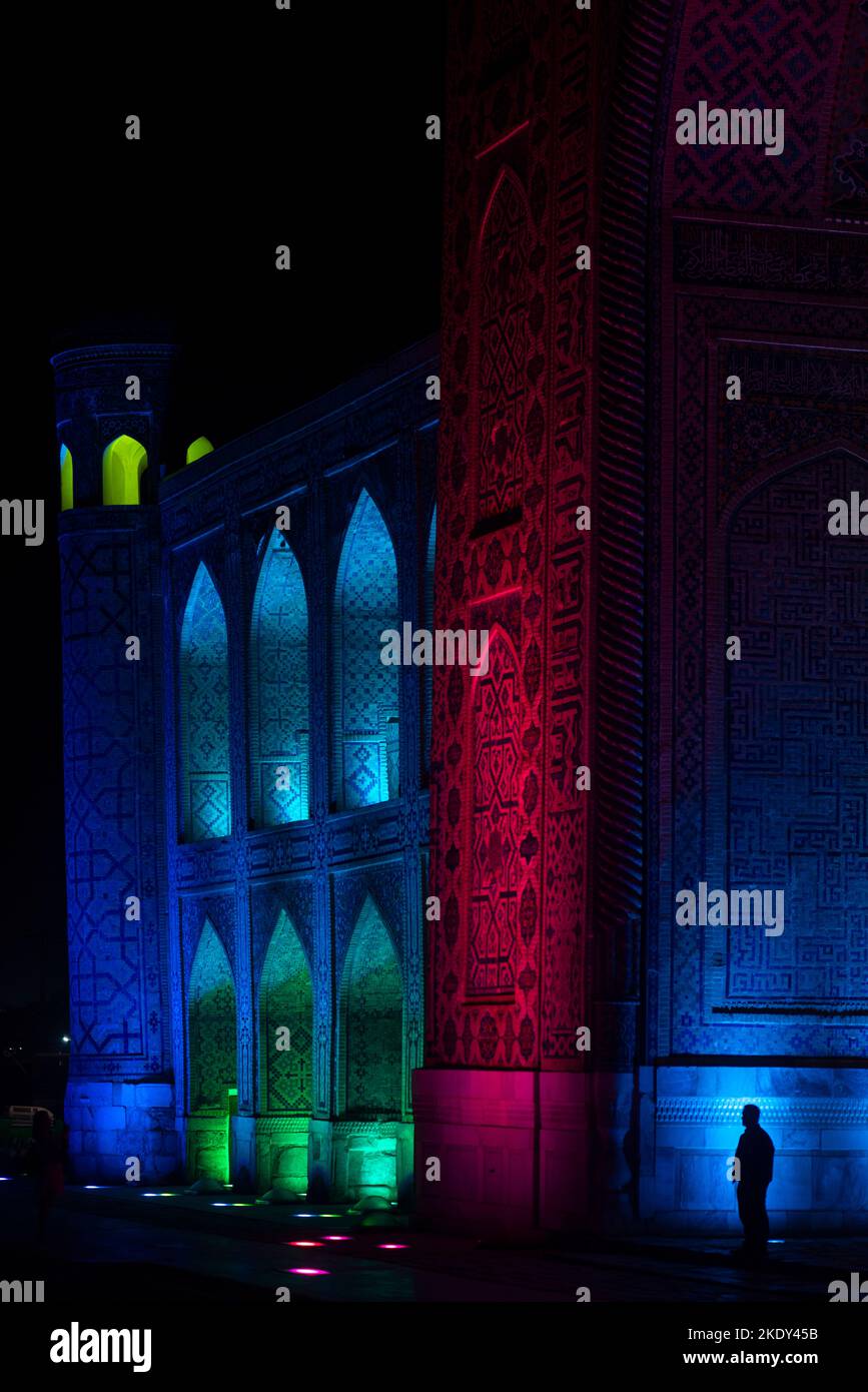 man standing by colorfol laser show in the registan square, samarkand ...