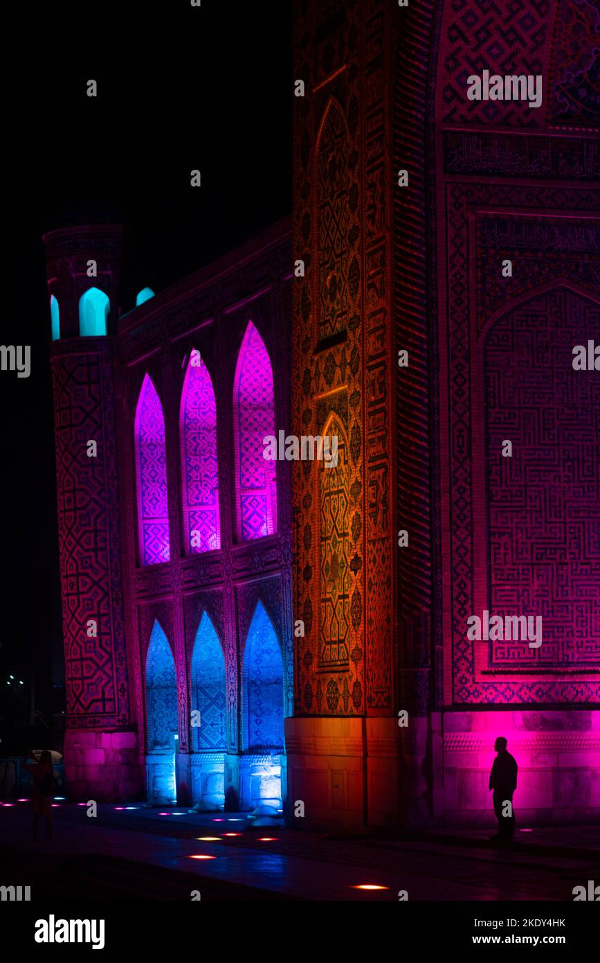 man standing by colorfol laser show in the registan square, samarkand ...