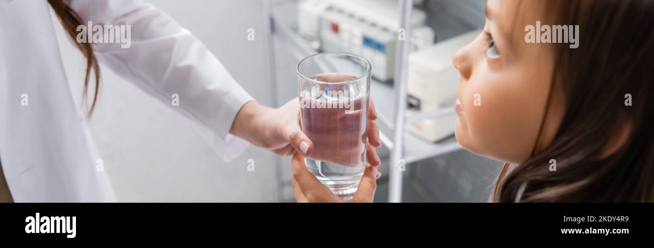 Pediatrician holding glass of water near kid in hospital ward, banner ...