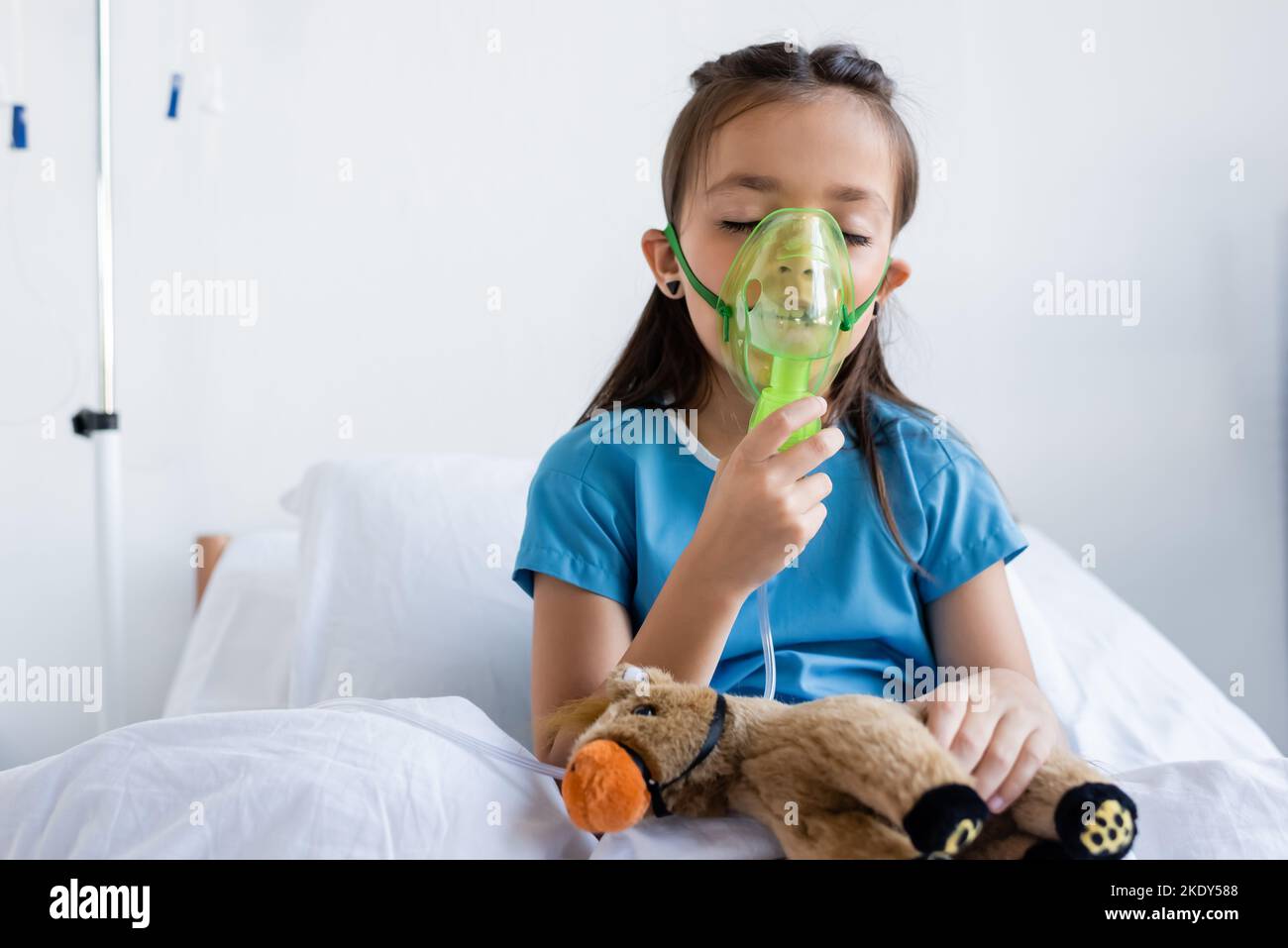 Sick child using oxygen mask near toy on bed in hospital,stock image ...
