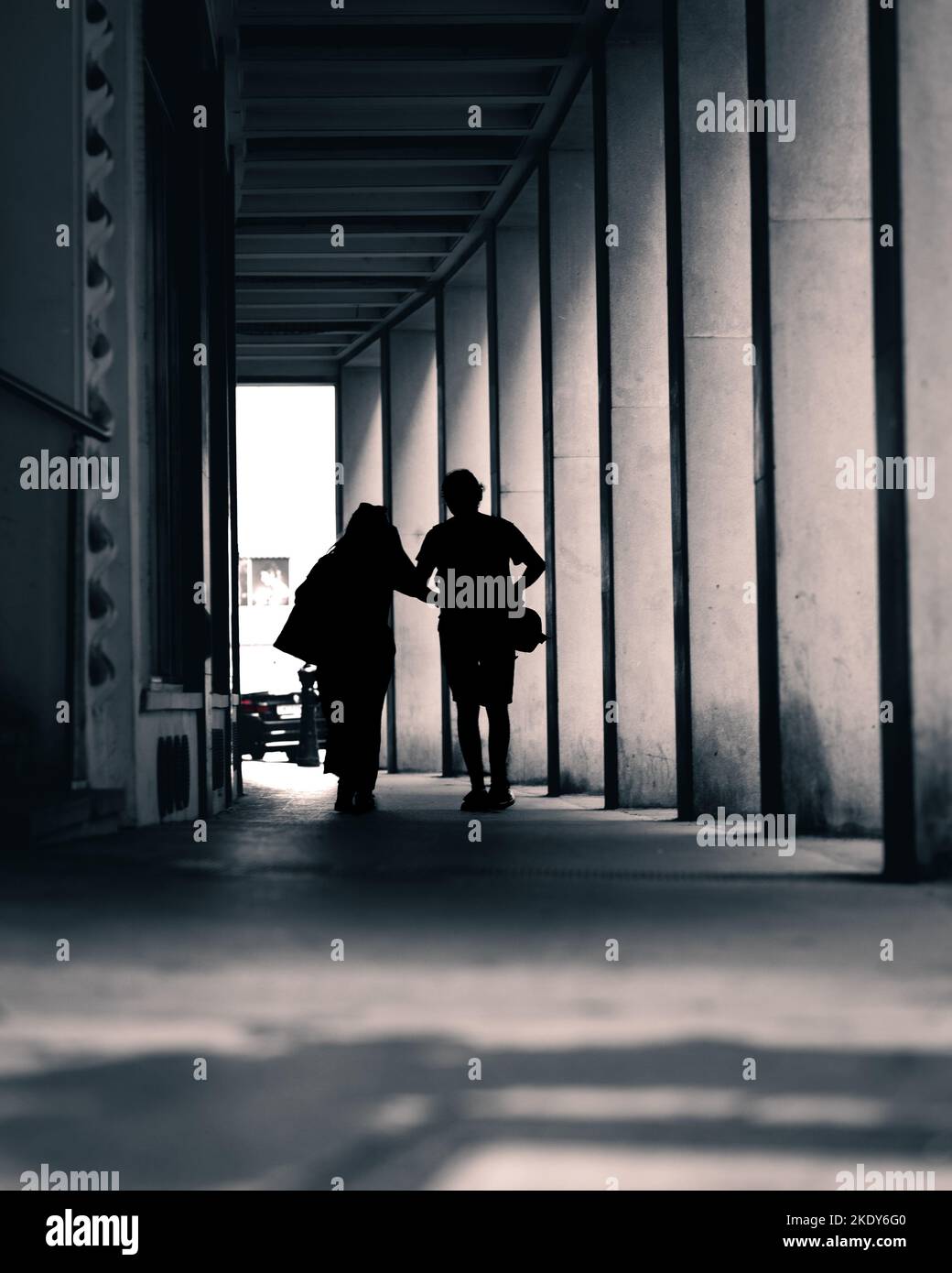 A vertical shot of a couple walking down a path with pillars Stock ...