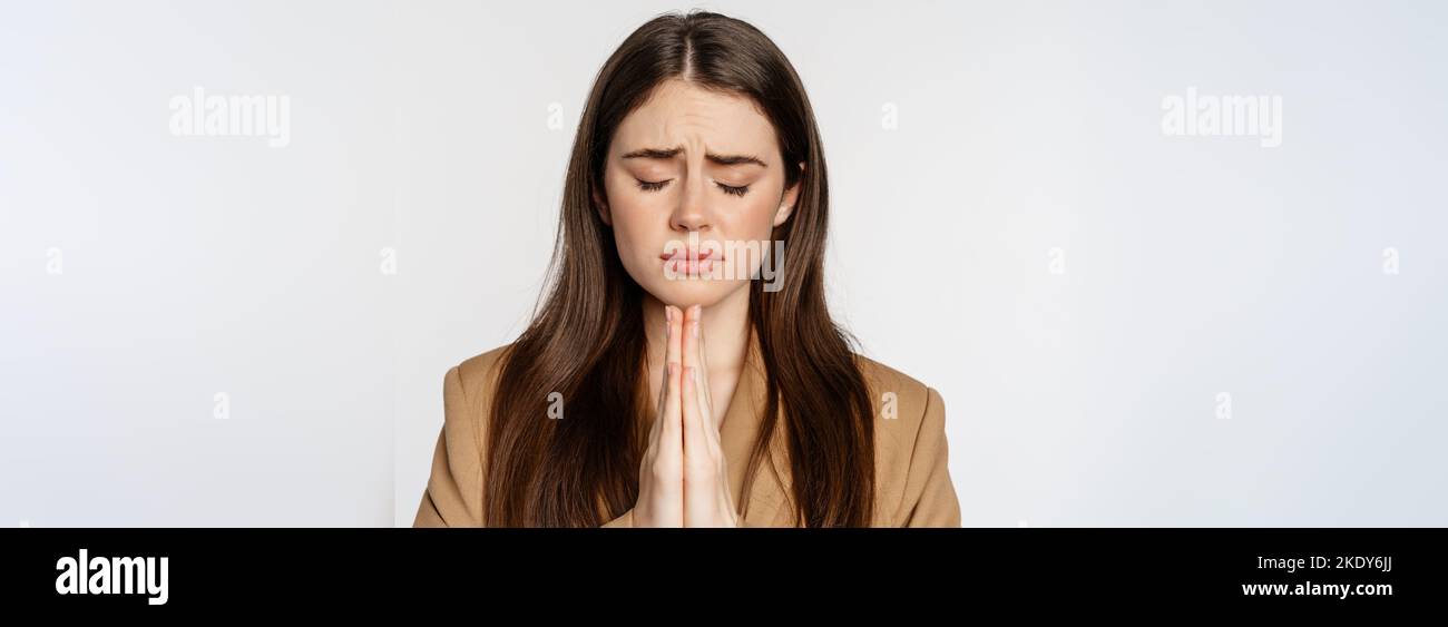 Sad hopeful businesswoman praying, close eyes and supplicating, close ...
