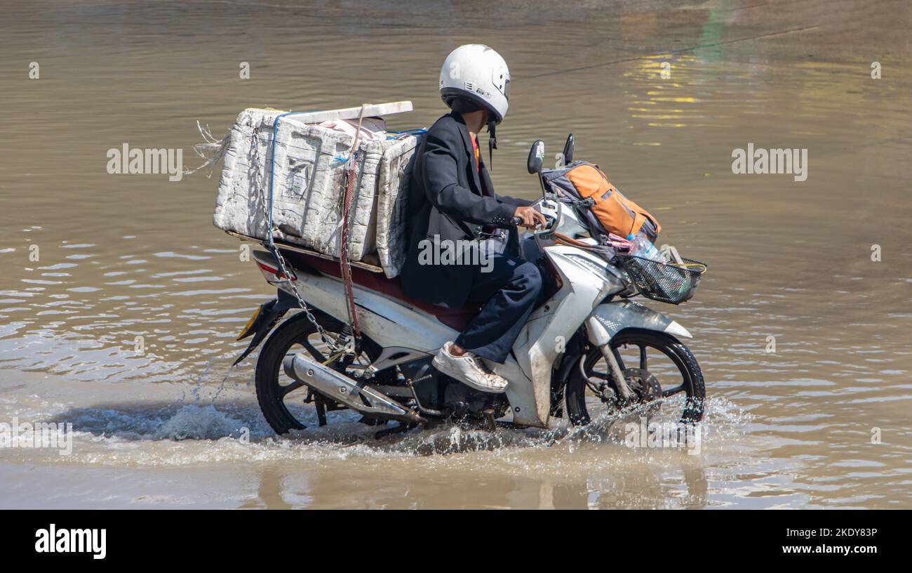 A man drives a load on a motorcycle through a flooded street Stock ...