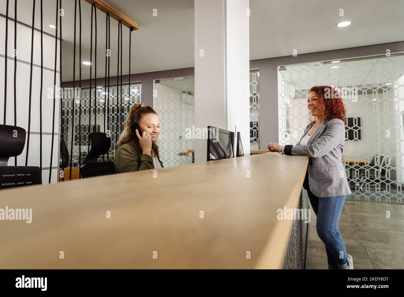 Receptionist on phone confirming guest has arrived fro meeting. Woman ...