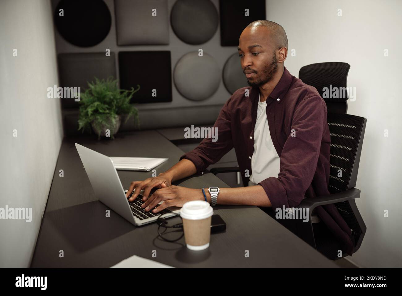 African business man sitting in office cubicle typing on laptop. Freelance entrepreneur working ...