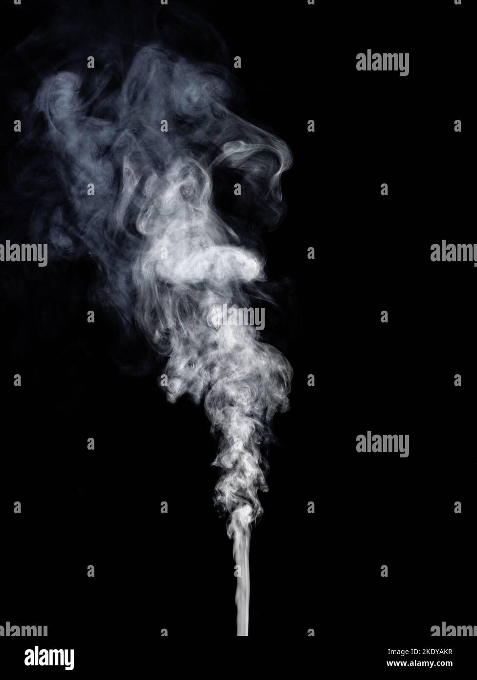 A jet of white smoke curls and swirls and rises up against a black ...