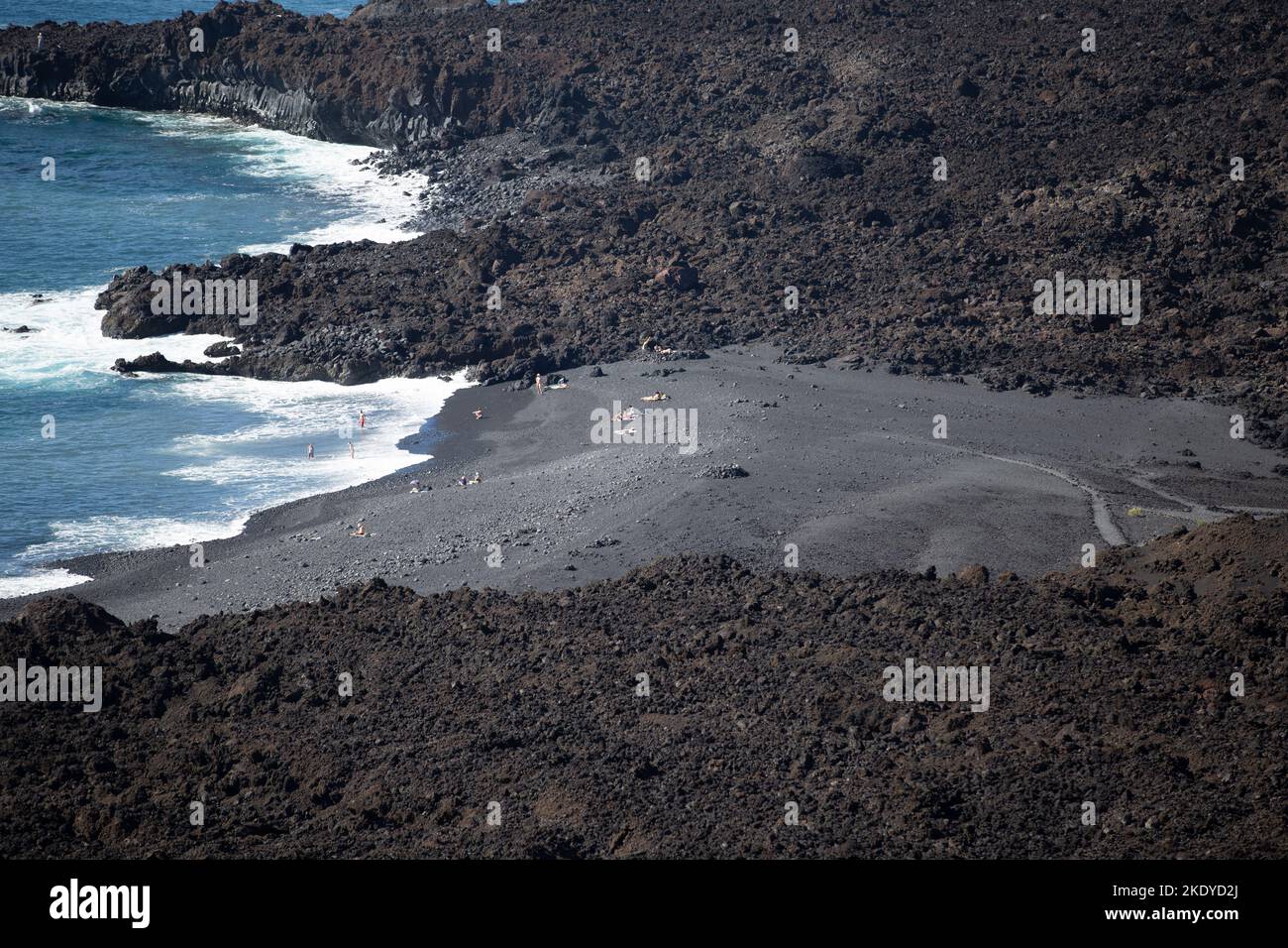 A shot of waves washing the gray sand beach surrounded by soil Stock ...