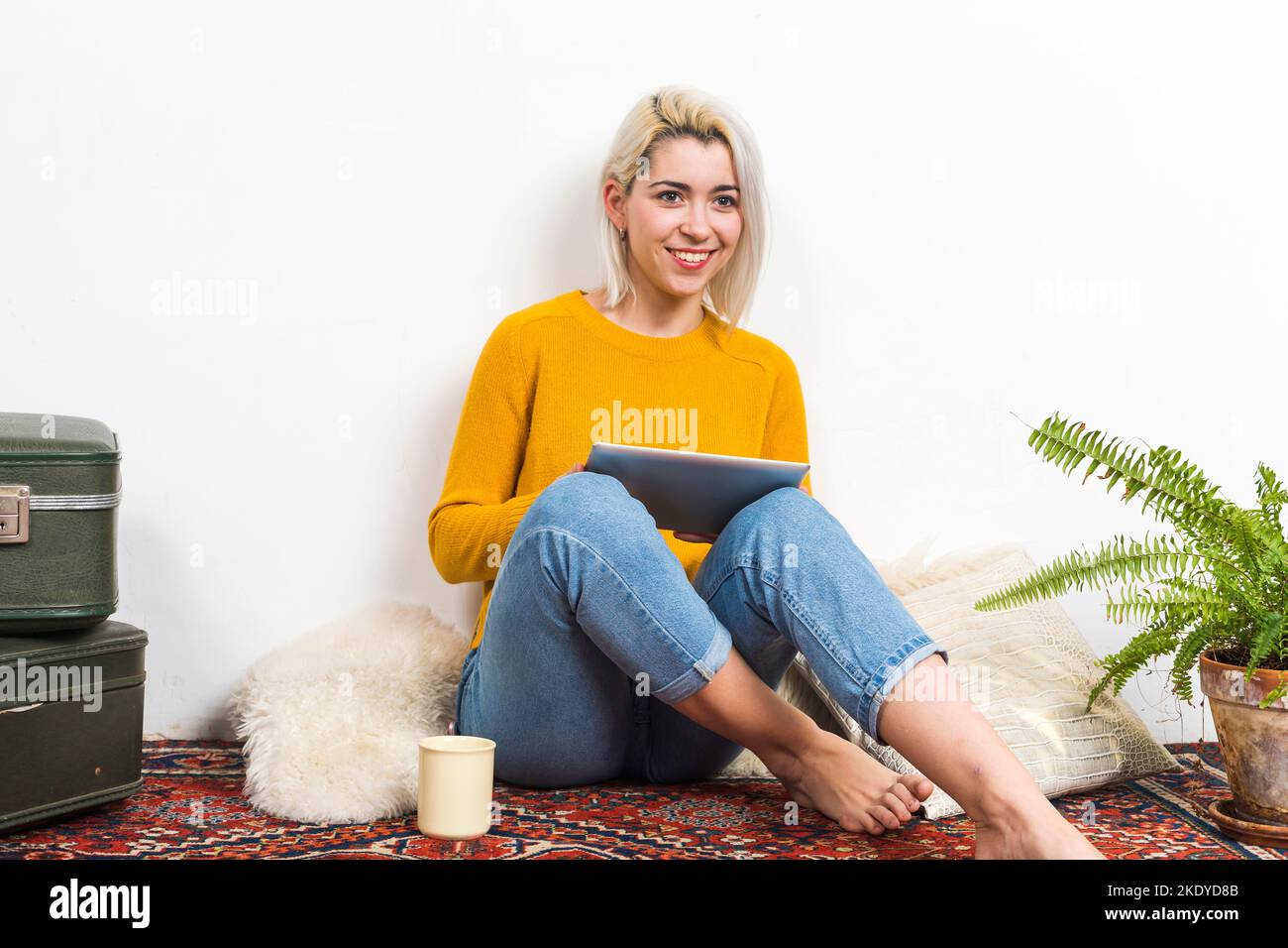 Technology and coziness. Beautiful young woman with cup of tea using ...