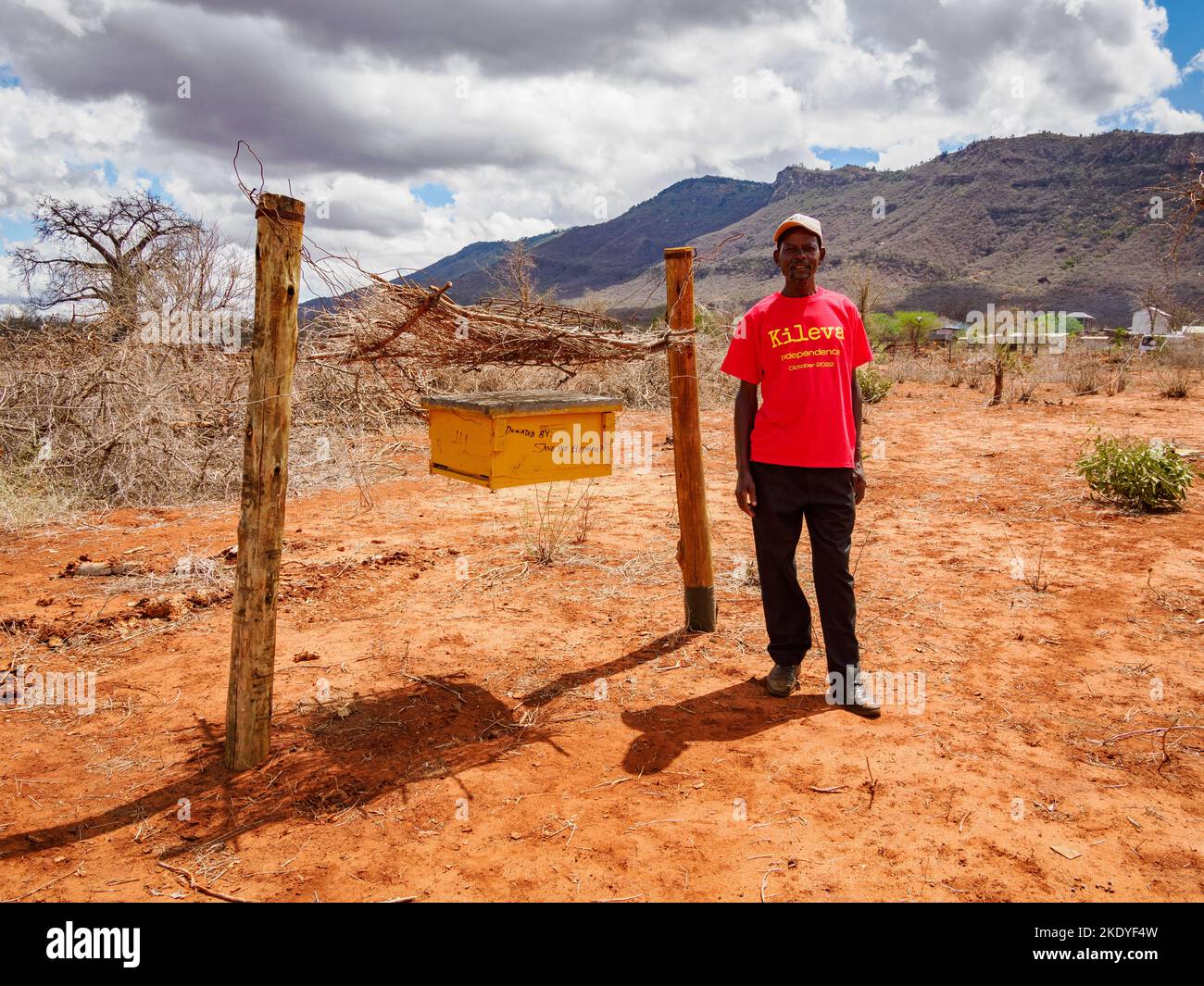 A farmer inspecting his beehive fence designed to deter elephants from ...