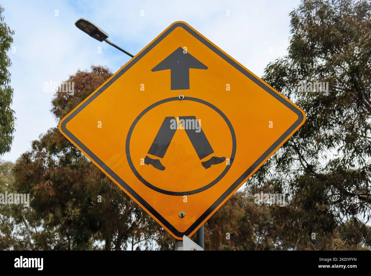 A closeup shot of a yellow pedestrian direction sign in a park Stock ...