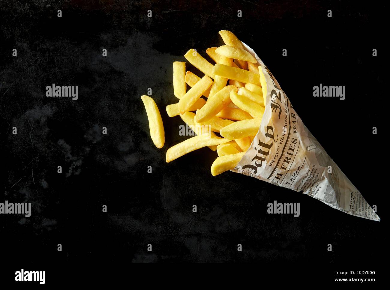 A top view of yummy potato chips wrapped in newspaper sheet and placed ...