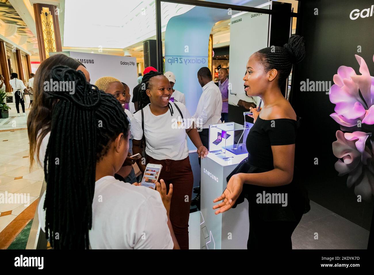A group of customers viewing Samsung phone at mall pop-up retail stand ...