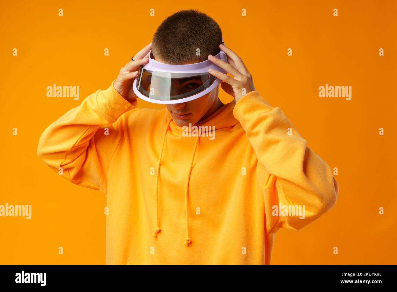 Young urban style man in sweatshirt and visor on yellow studio ...