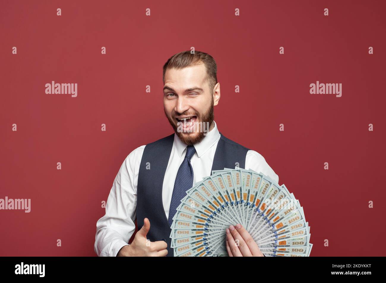 Excited successful businessman winking and showing thumb up with money ...