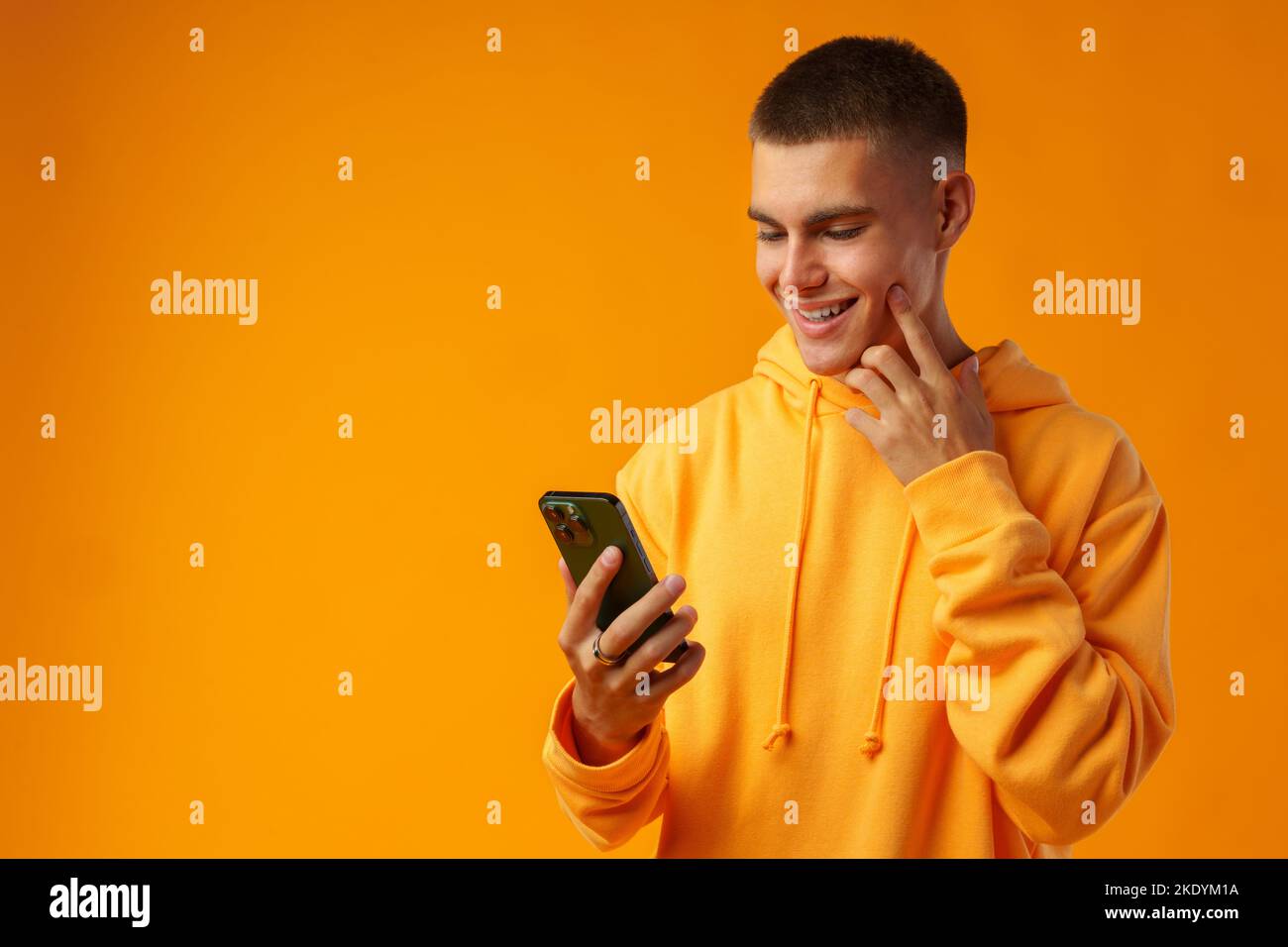Portrait of a smiling young man holding mobile phone on yellow ...