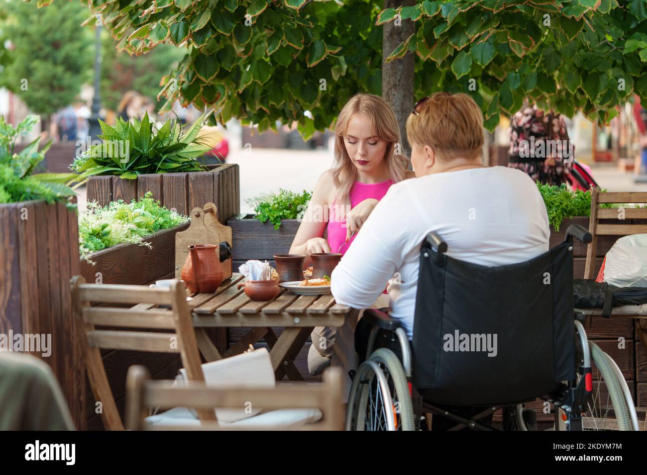 Woman wheelchair user dining at a restaurant with her young daughter ...