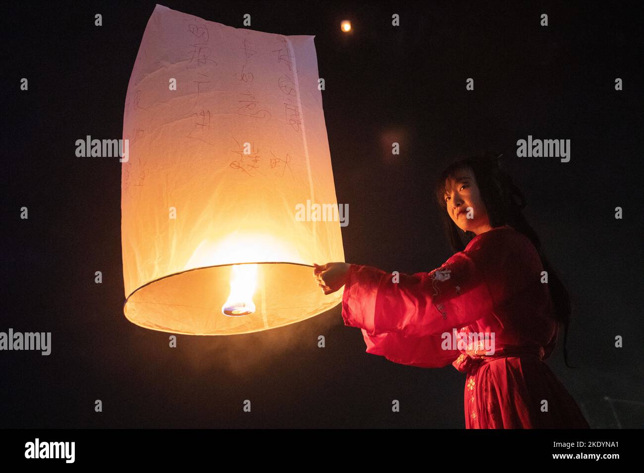 A woman wearing a traditional Chinese costume holds a lantern during Yi Peng (Yee Peng) Festival ...