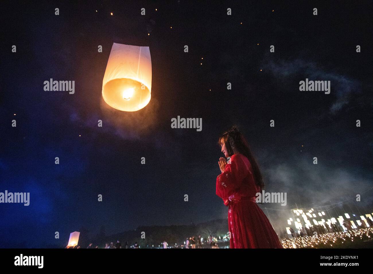 A woman wearing a traditional Chinese costume prays after releasing a lantern during Yi Peng ...