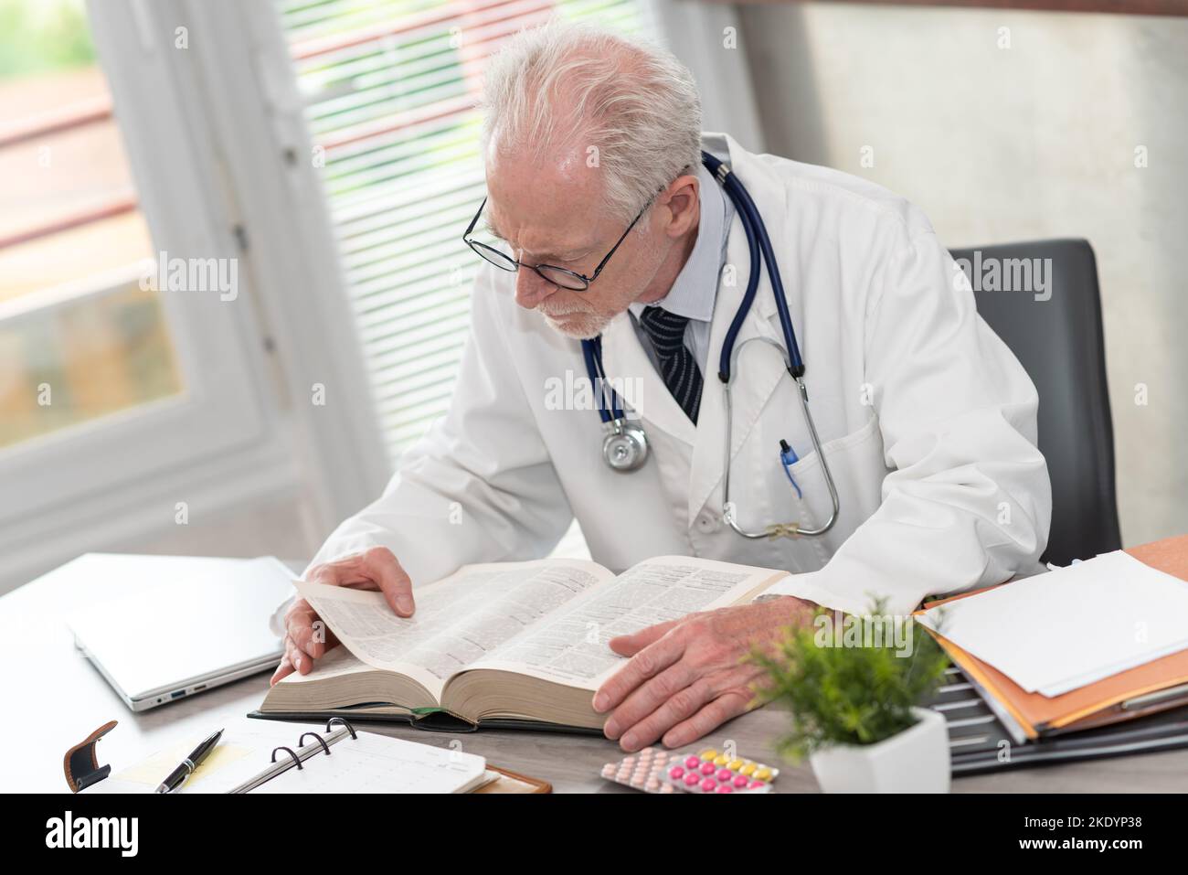 Senior doctor reading a textbook in medical office Stock Photo - Alamy