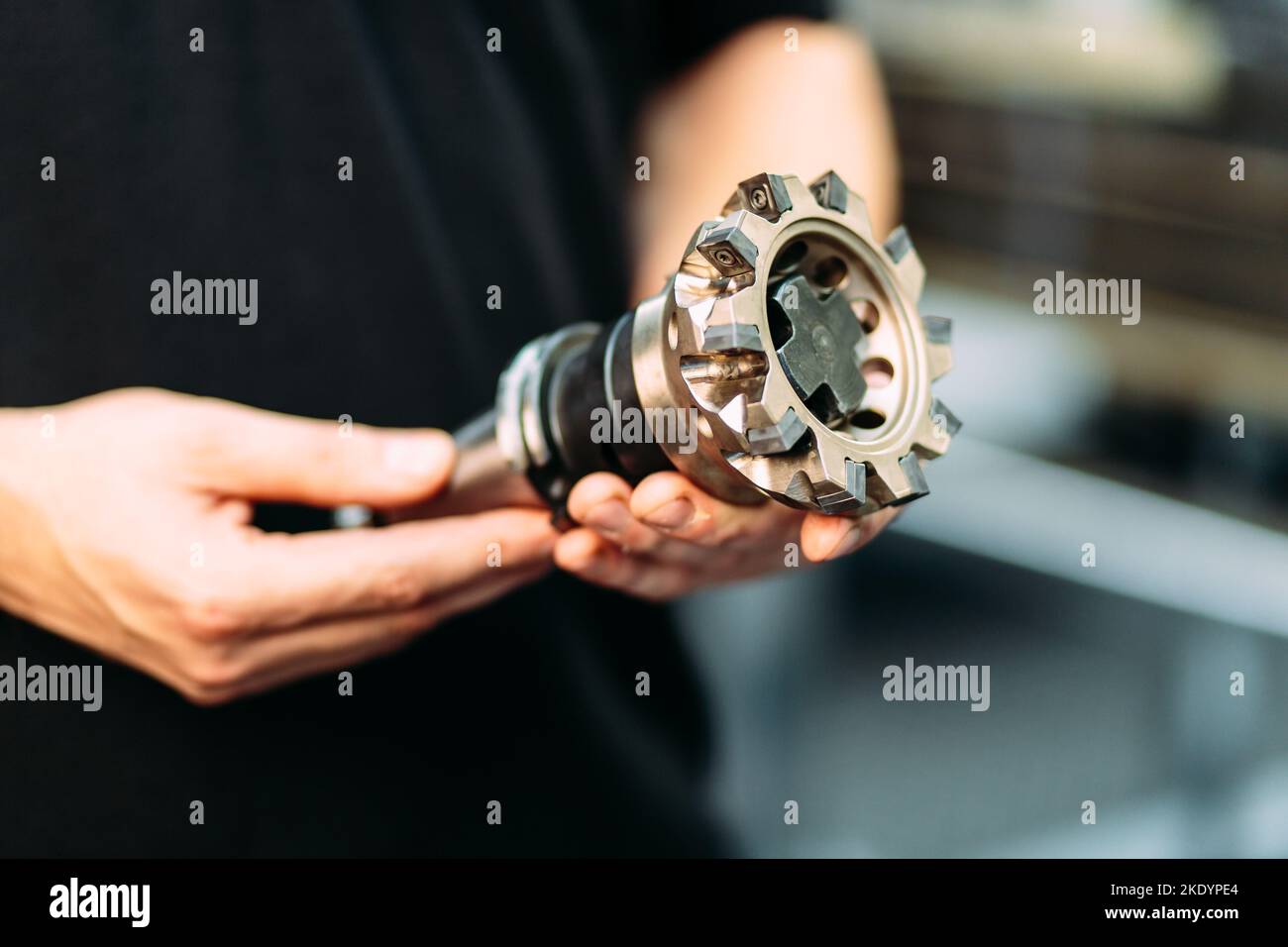 A man holding a milling tool in his hands wearing a black shirt working ...