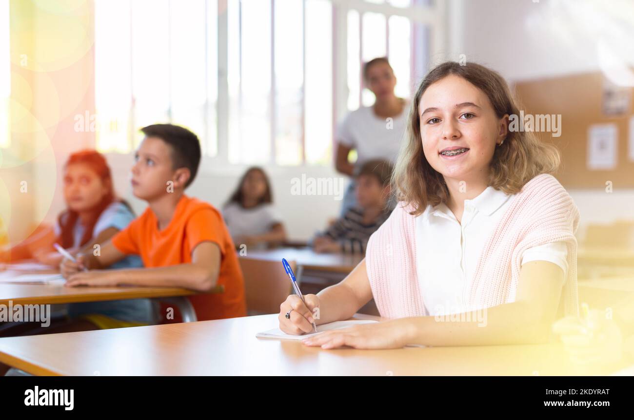 Smiling diligent teenage girl sitting in classroom during lesson Stock ...