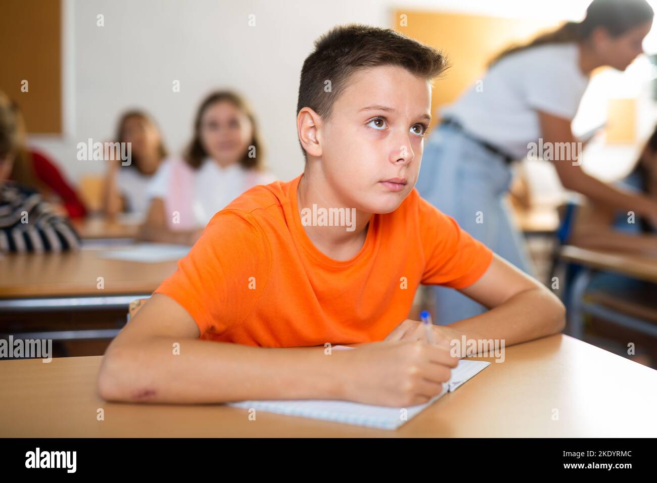 Diligent tween boy making notes of teacher lecture in class Stock Photo ...