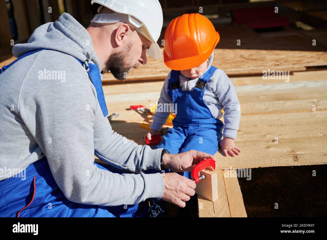 Father with toddler son building wooden frame house. Male builder ...