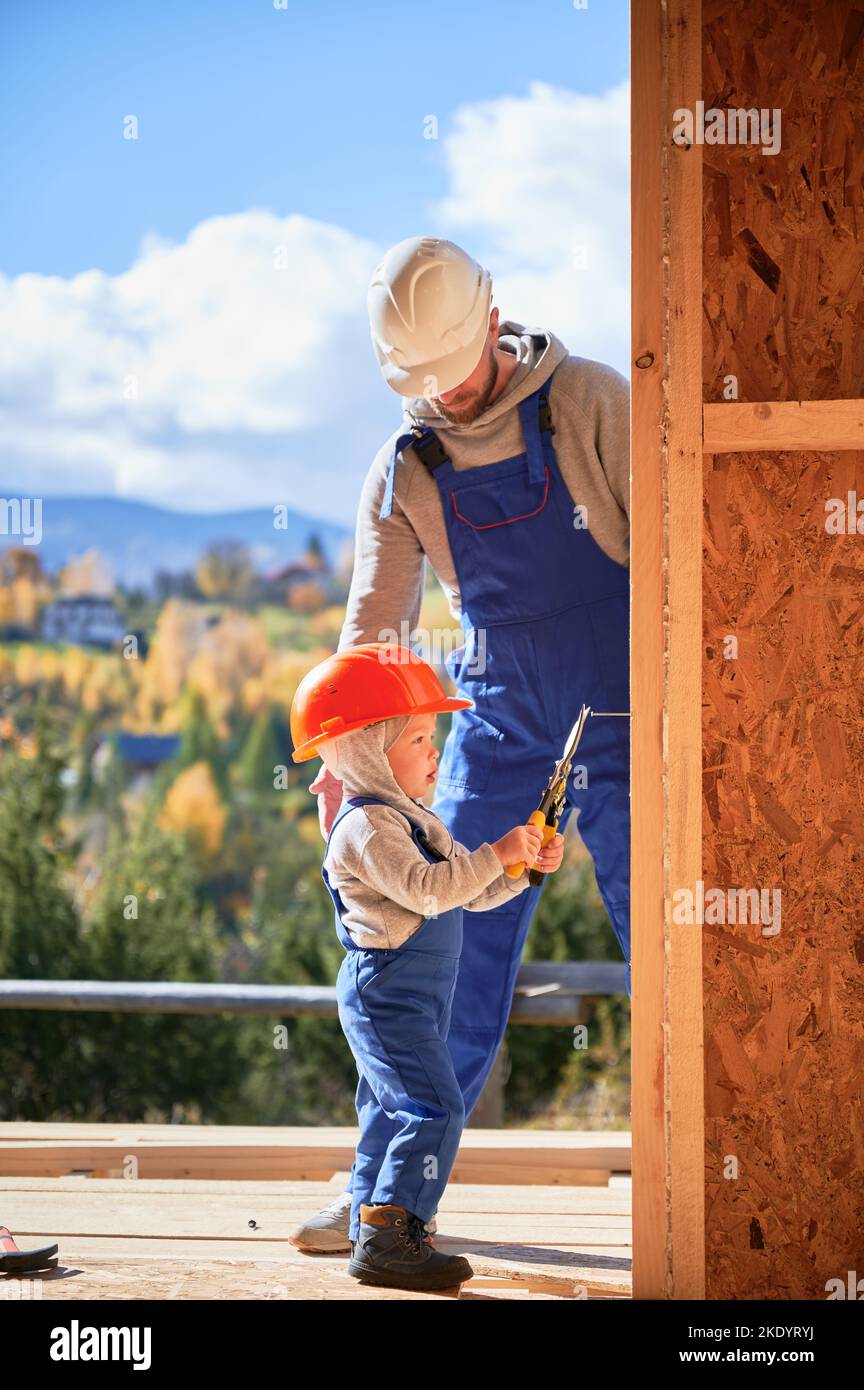 Father with toddler son building wooden frame house. Boy helping his ...