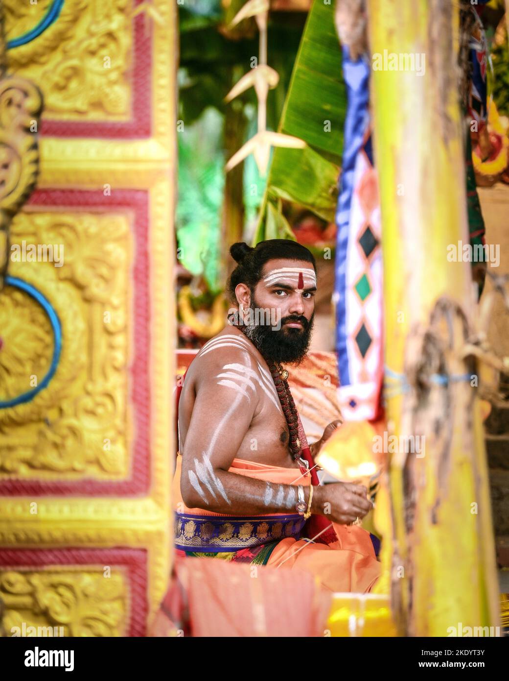 A vertical portrait of a Hindu Priest painted and with colorful clothes ...