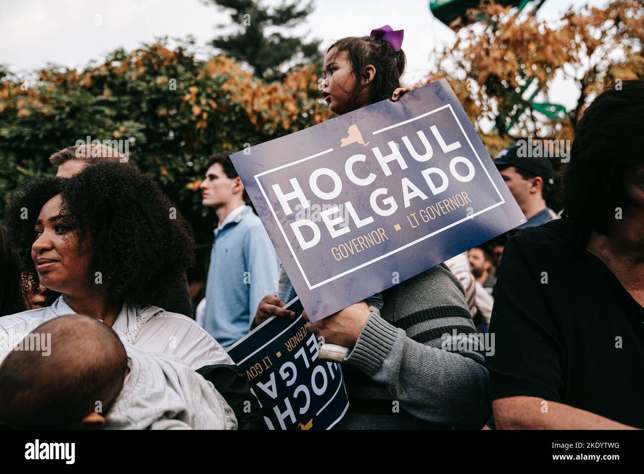 A young child holds a Hochul/Delgado sign while sitting on her father's ...