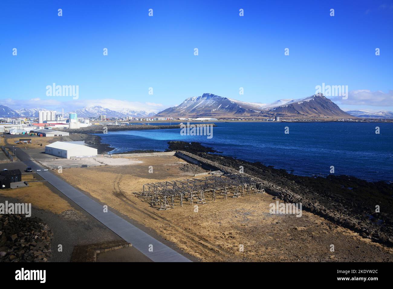 A scenic shot of a snowy mountain across the sea with a rocky beach in ...