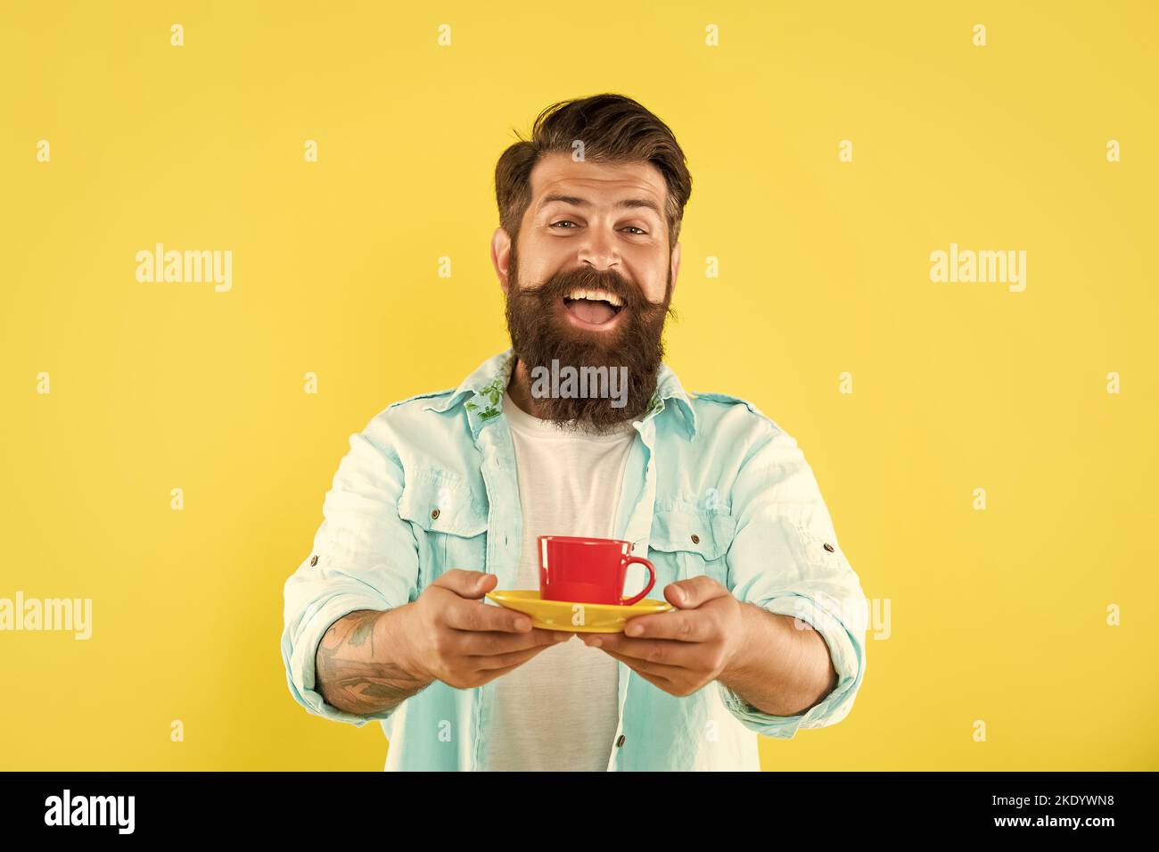 Happy caucasian guy smile giving cup of hot beverage yellow background ...