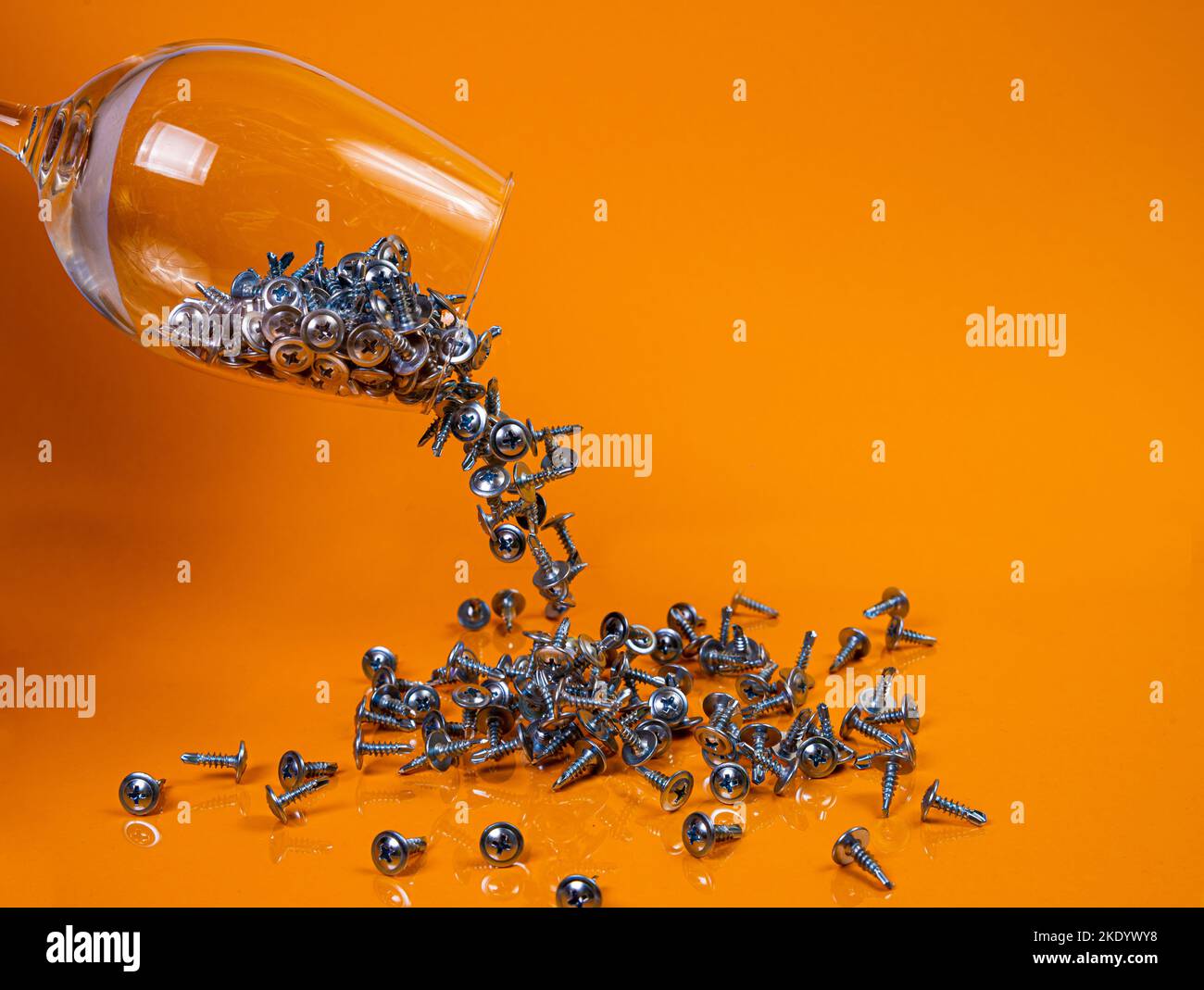 Dropped Many metal self-tapping screws made of steel in a glass, in ...