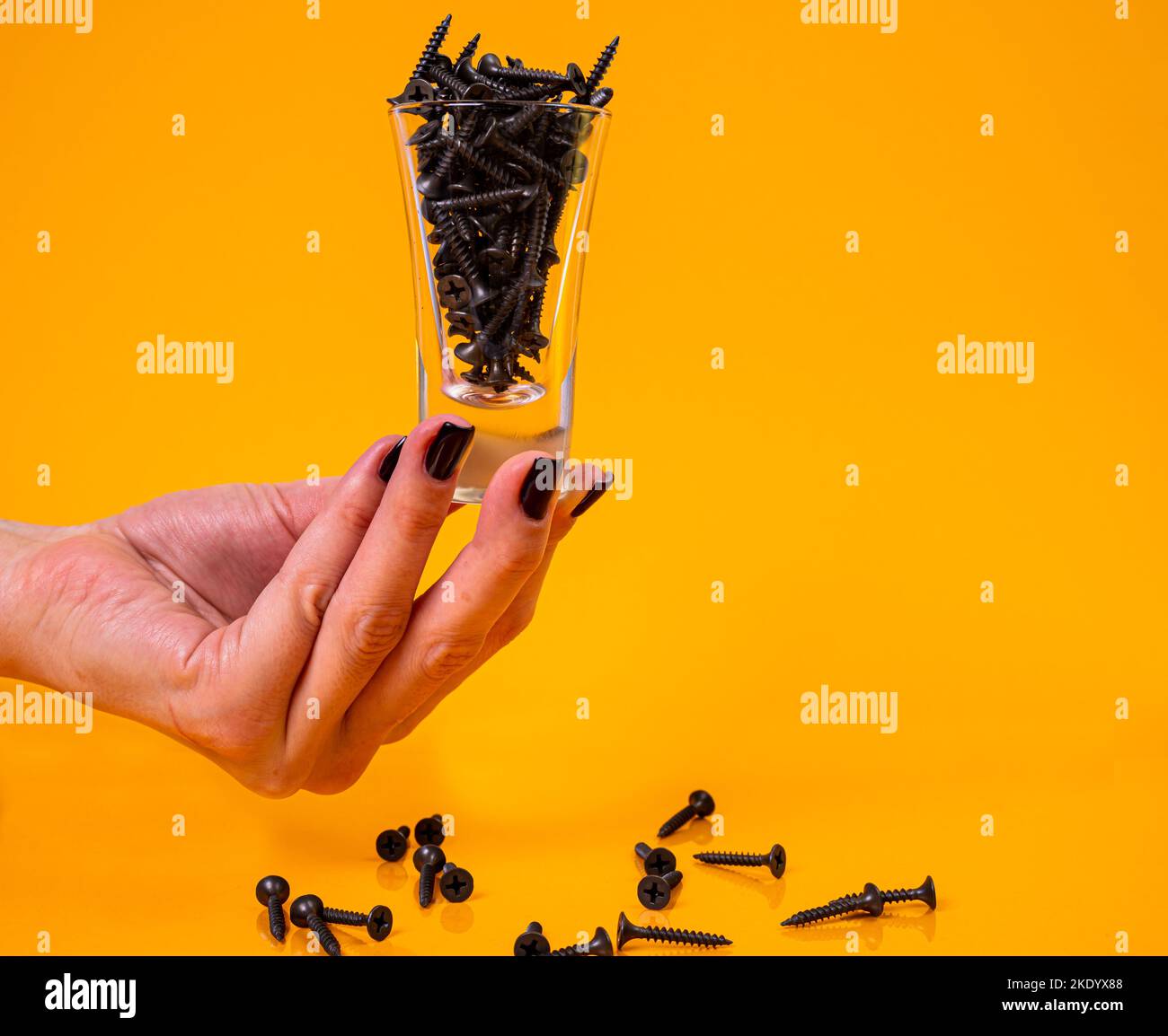 Dropped Many metal self-tapping screws made of steel in a glass, in ...