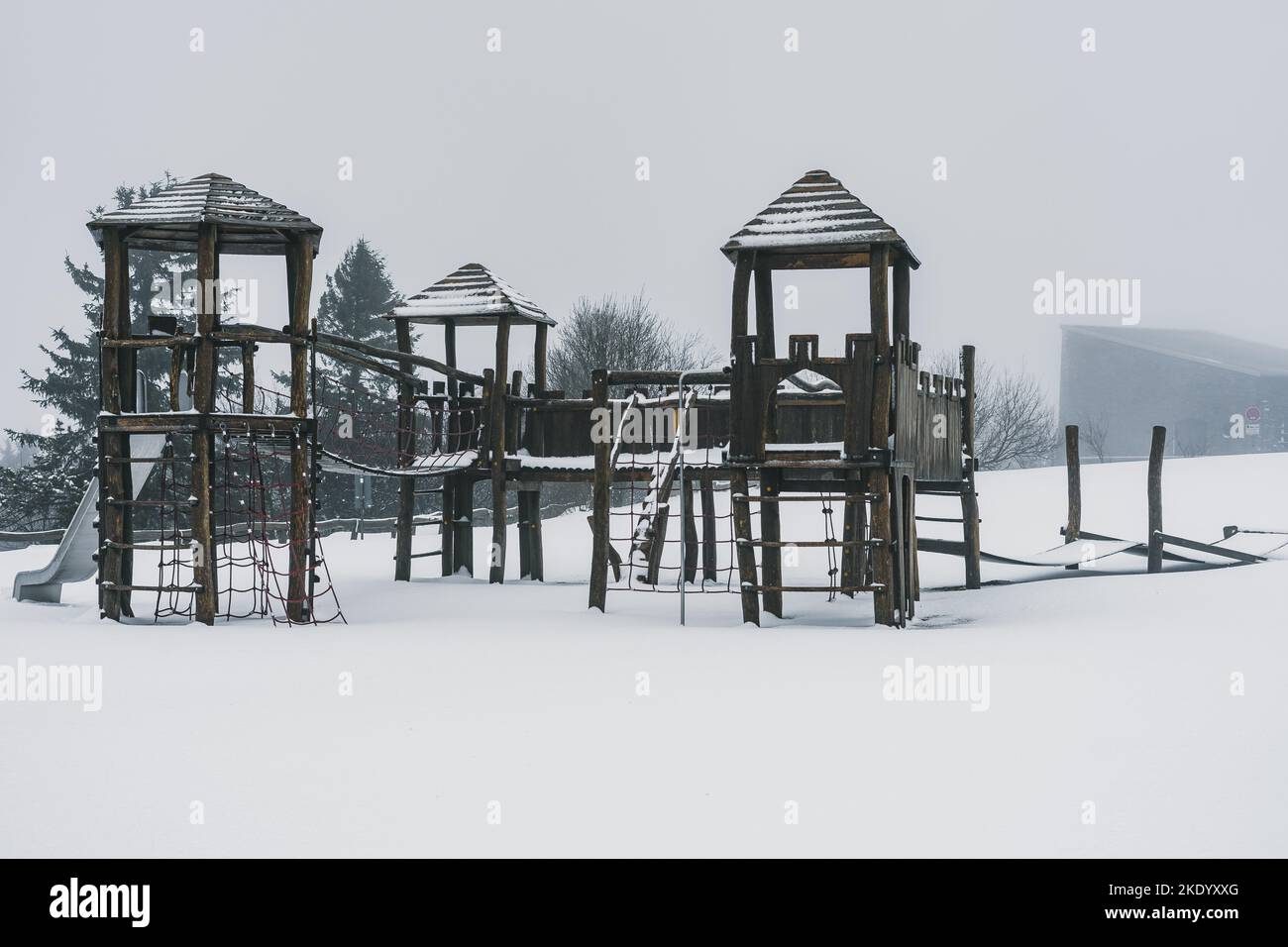A beautiful playground in a park covered in snow on a cold and misty ...