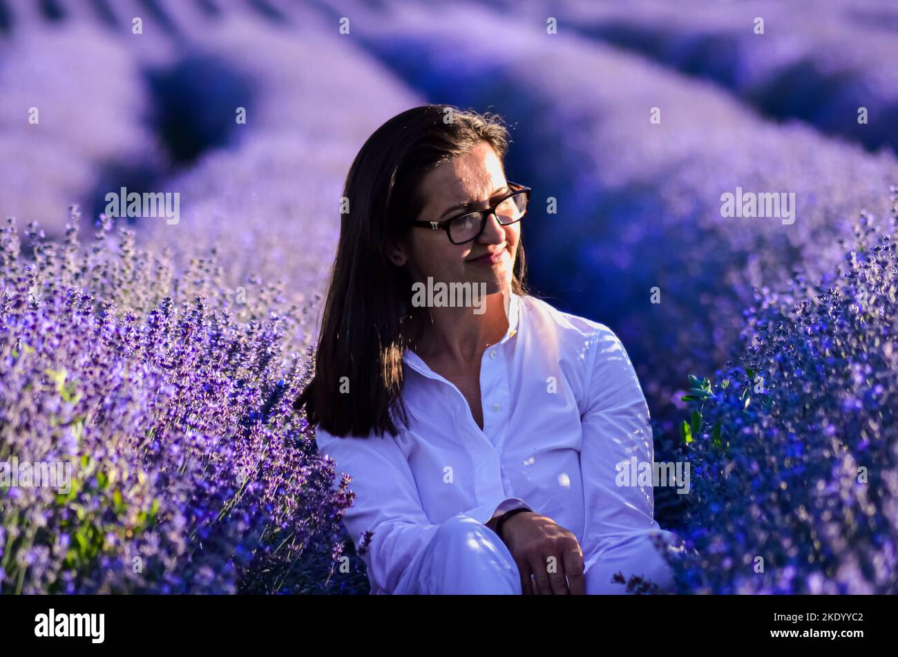 A beautiful Caucasian woman in eyeglasses and a white shirt sitting in ...