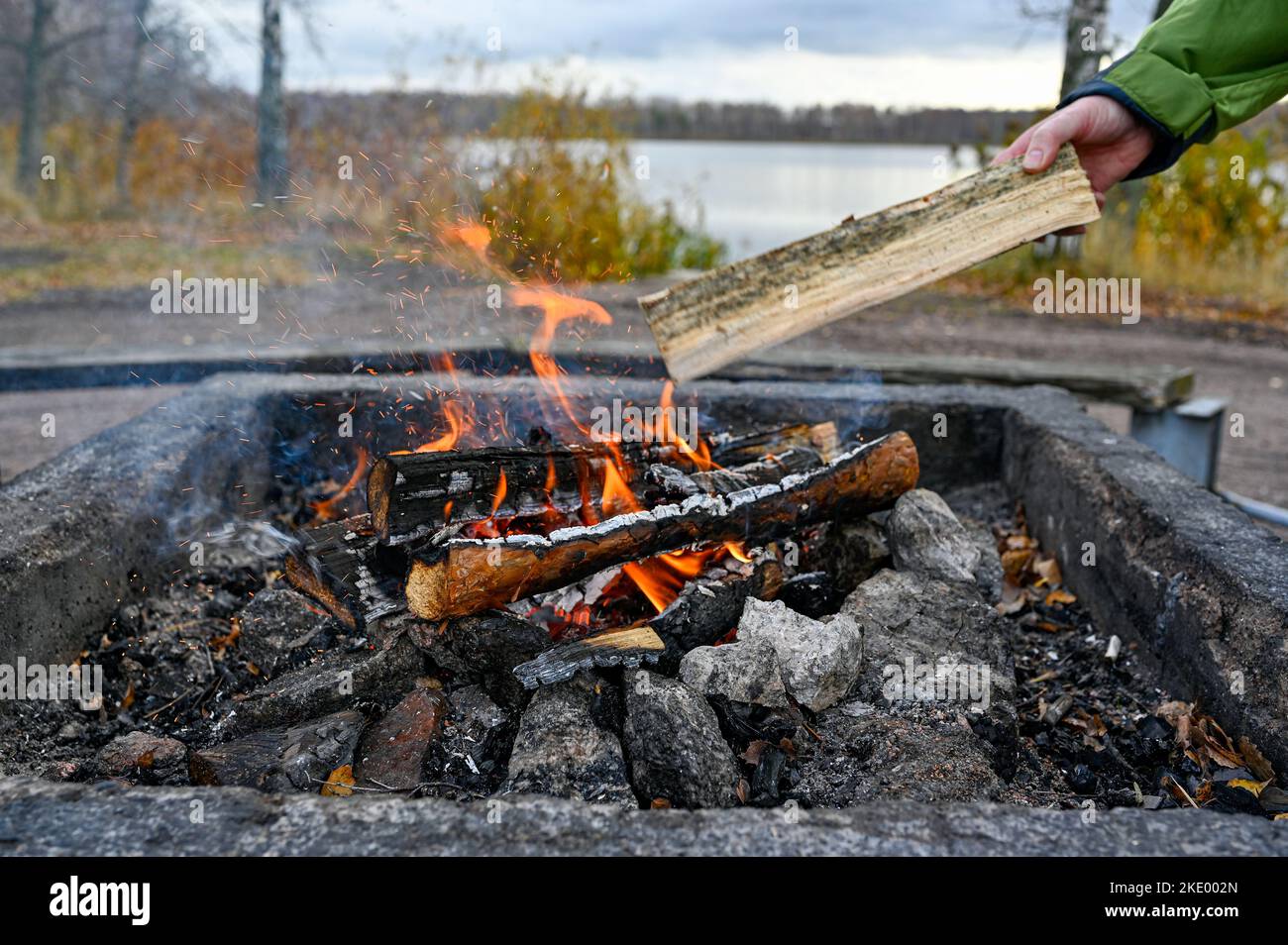 hand putting firewood on fire at camping Stock Photo - Alamy