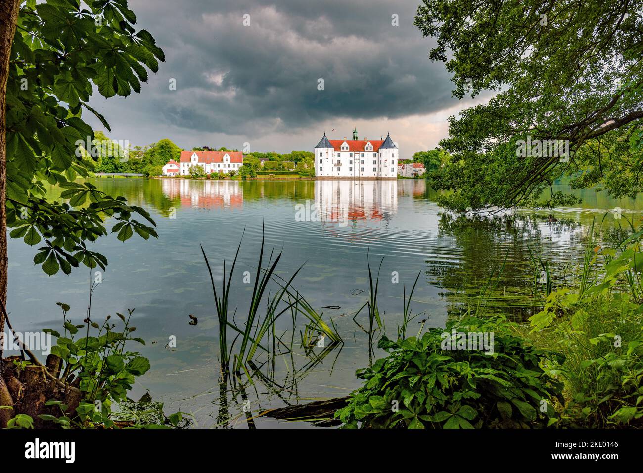 The medieval Glucksburg Castle in Germany surrounded by green trees and ...