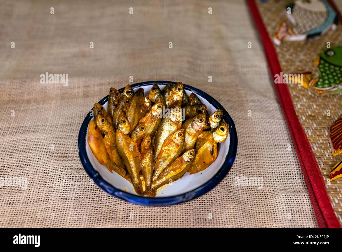A closeup shot of Mourala fish cooked in yellow gravy in a white ...