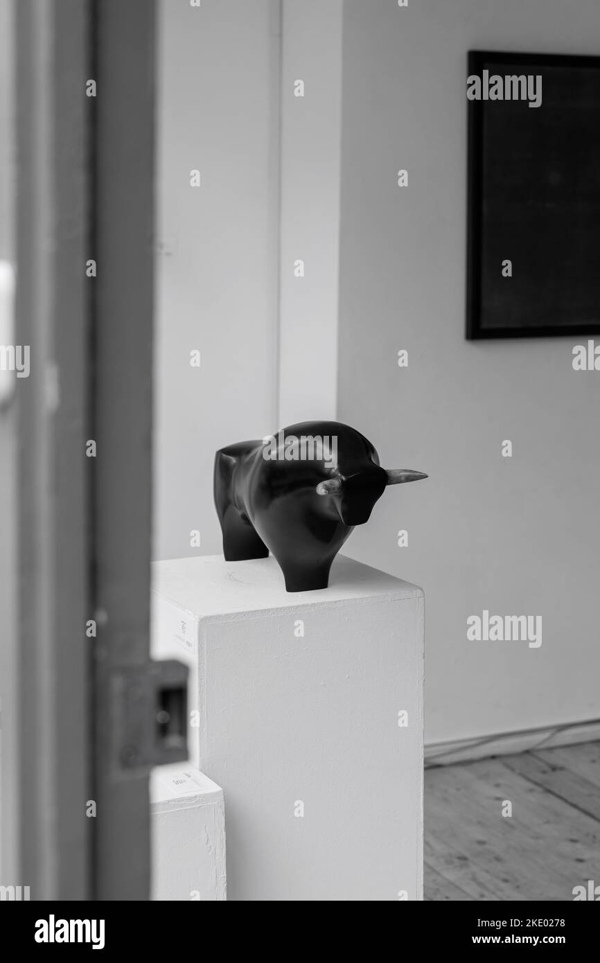 A vertical shot of a minimalist sculpture of a black bull on display in ...