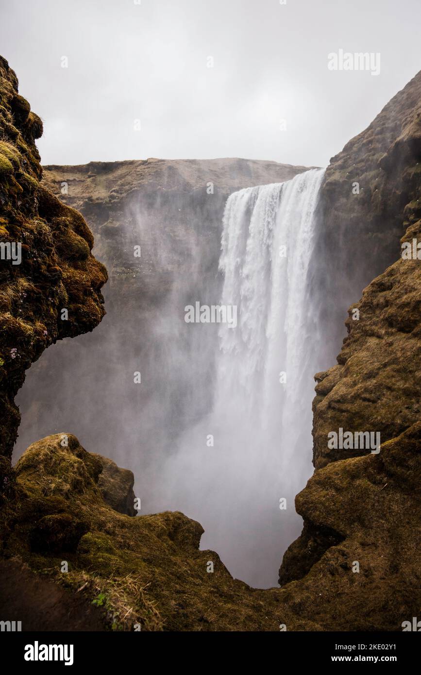 A vertical shot of the Skogafoss waterfall flowing down the cliff in ...