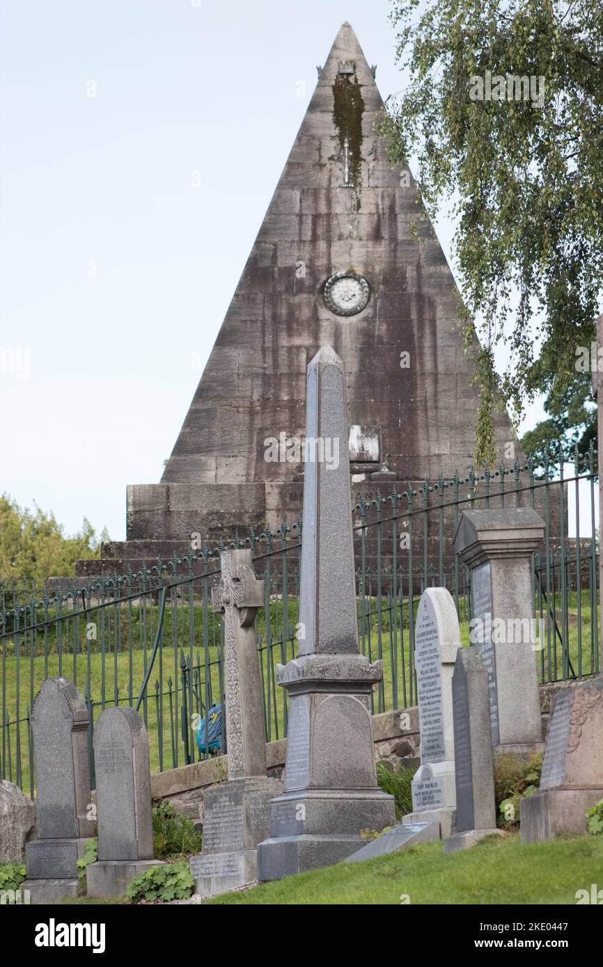 A vertical shot of a stone Pyramidal and tombs at the graveyard of ...