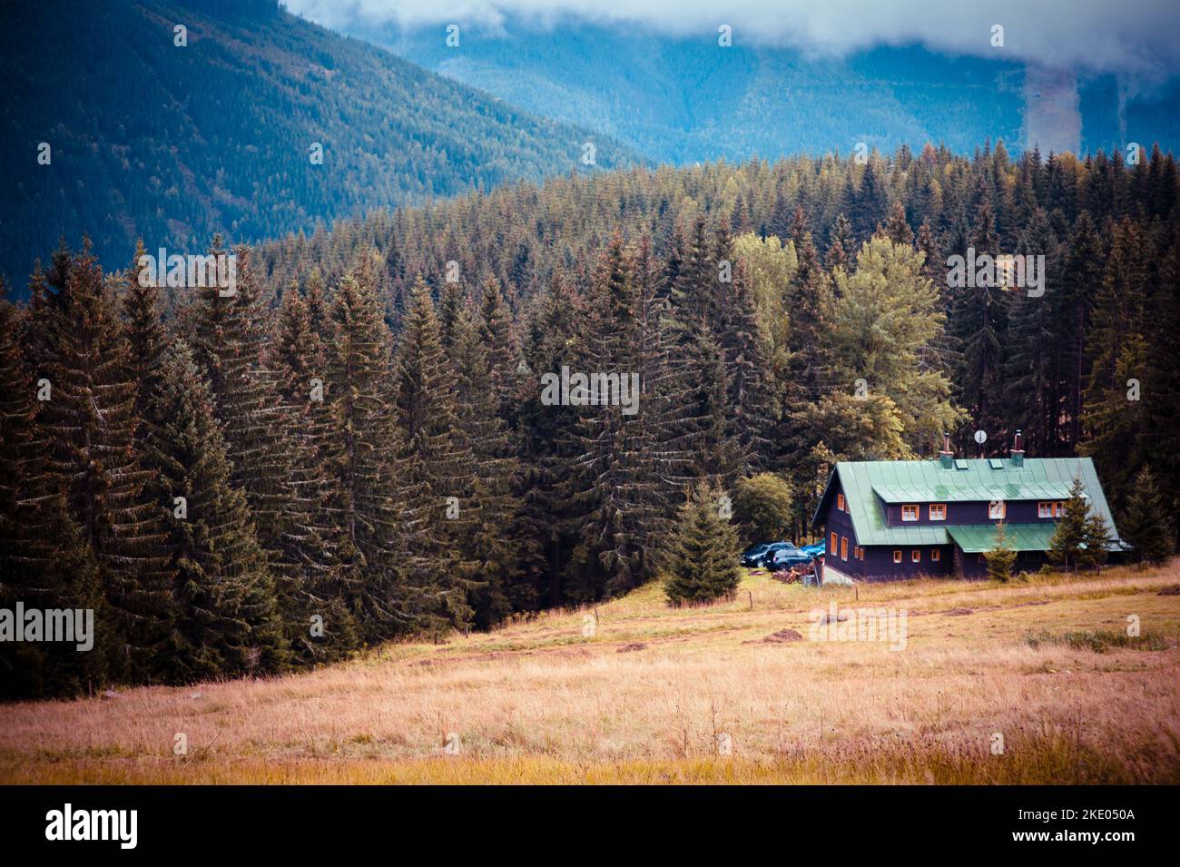 A countryside house in natural field with trees and mountain in the ...