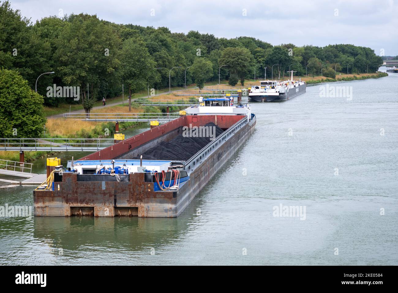 The barges moored to a canal with trees in the background under cloudy ...