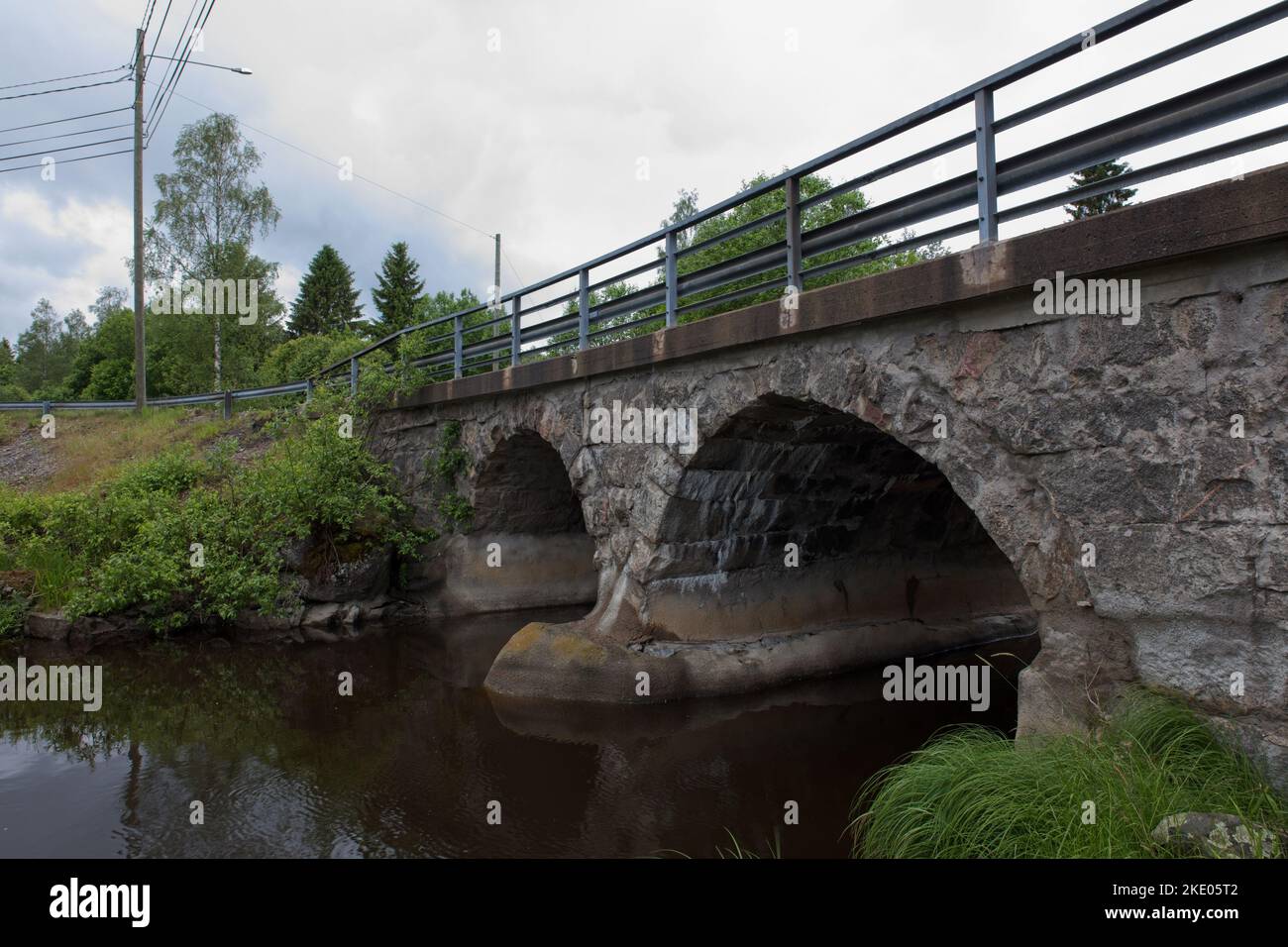 Two arch old stone bridge over Hirvihaaranjoki river in cloudy weather ...