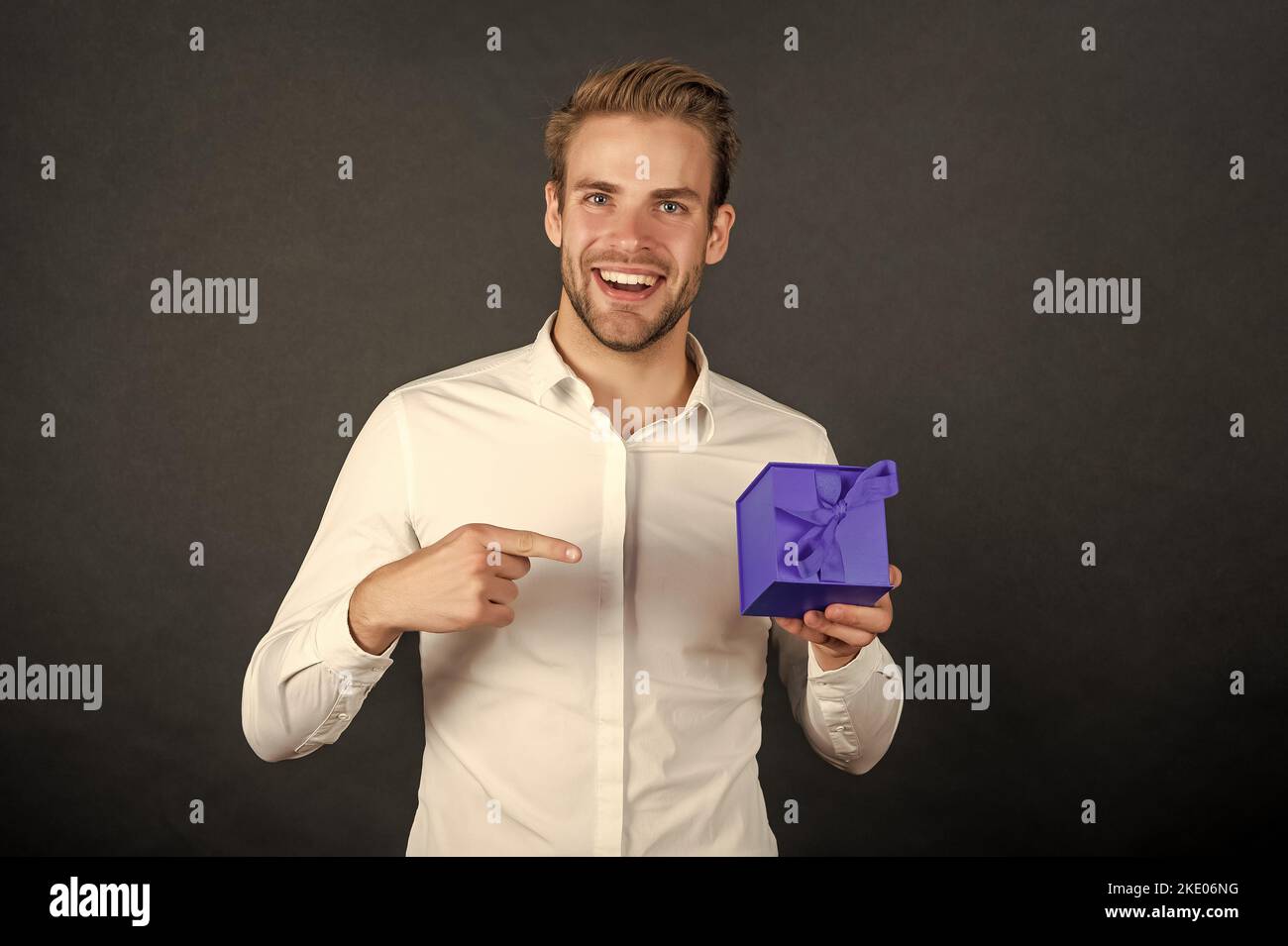 happy young man in suit pointing finger on birthday present box Stock ...
