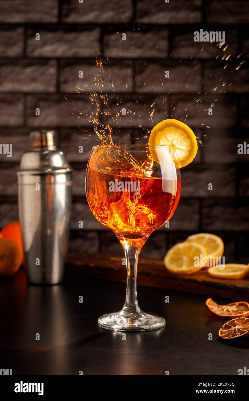 A splashing spritz cocktail with a lemon slice and steel cocktail ...