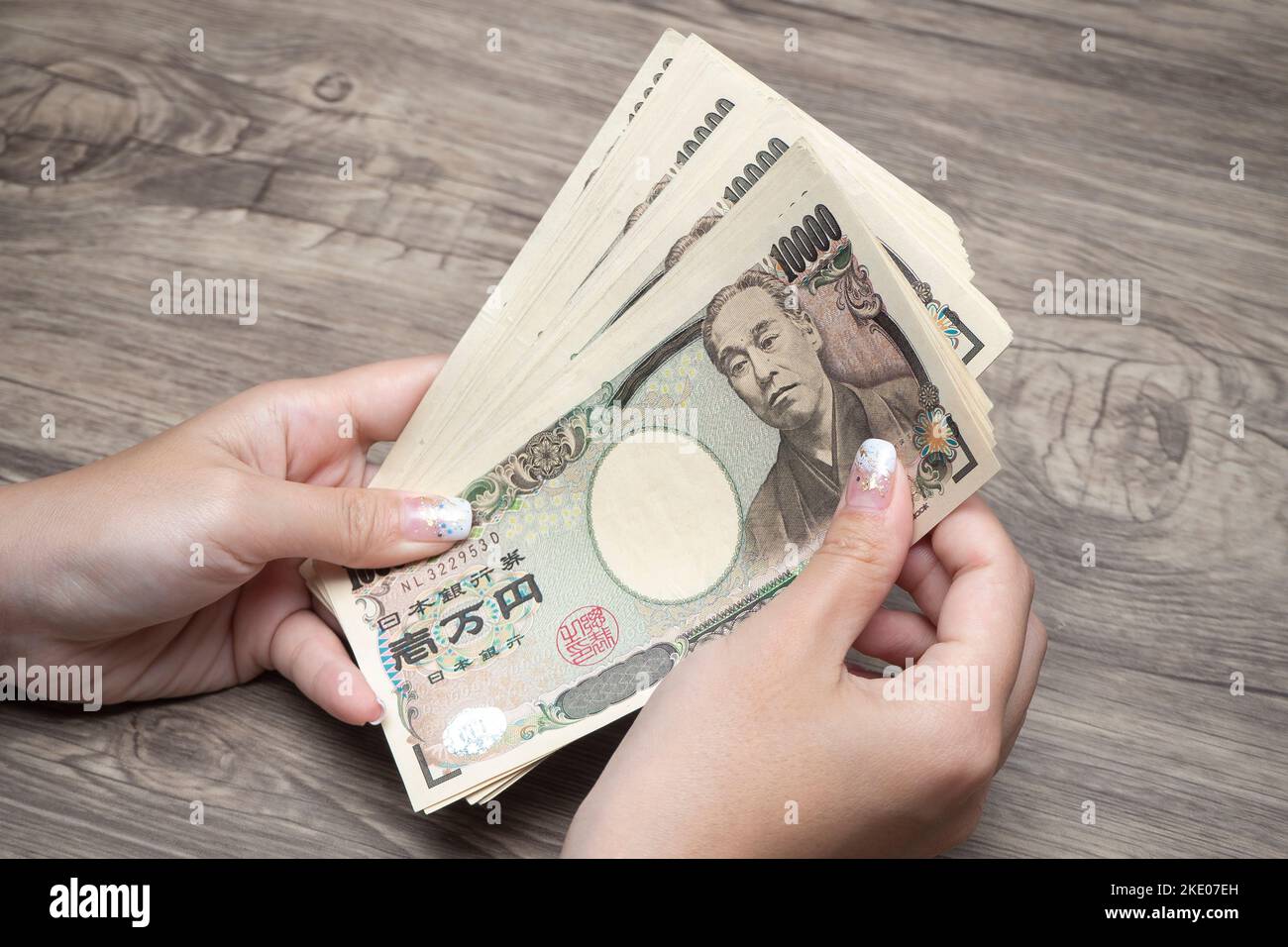 A female holding Japanese yen 10000 notes Stock Photo - Alamy