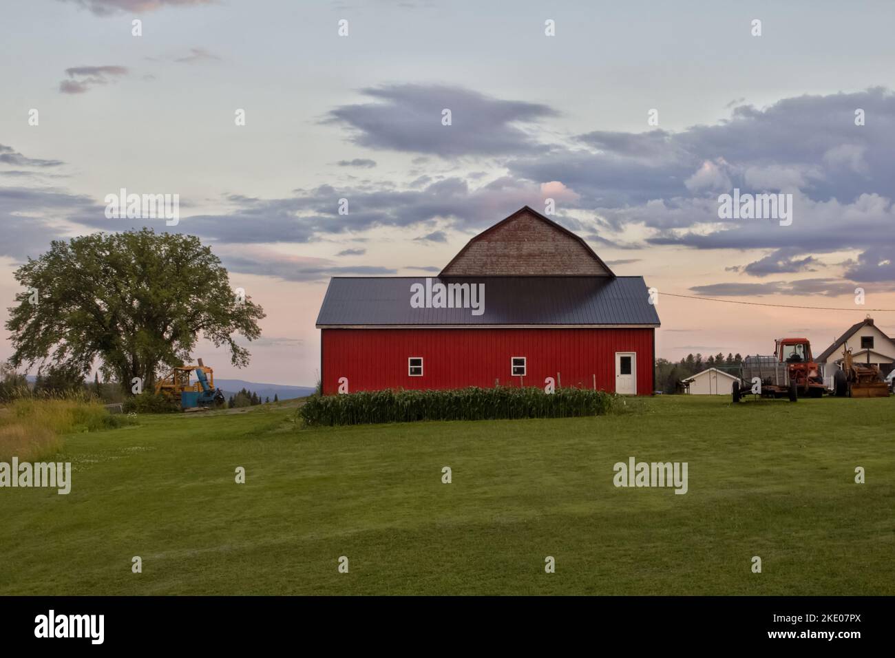 A beautiful view of a red barn in a green field against a mesmerizing ...